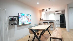 Uma cozinha moderna com micro-ondas, geladeira e um espaço de jantar com mesa e cadeiras de madeira.