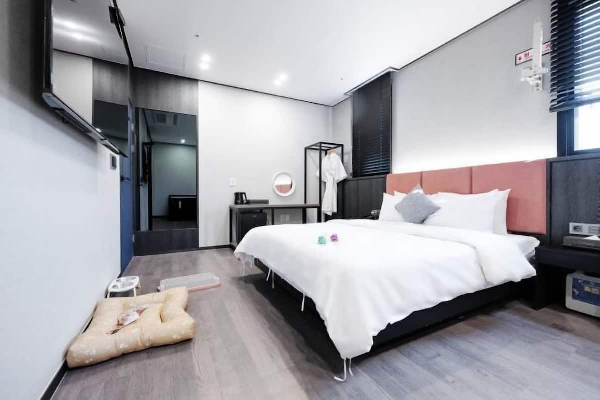 Quarto moderno com uma cama grande, mesa de cabeceira, espelho e guarda-roupa.