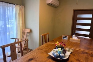 Uma mesa de jantar de madeira com uma bandeja de objetos, uma cadeira de madeira e uma janela com cortinas.