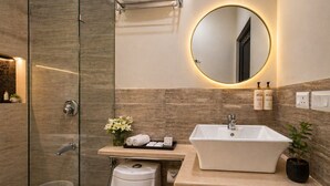 Um banheiro moderno com box de vidro, banheira livremente posicionada, toucador com espelho e artigos de higiene pessoal.