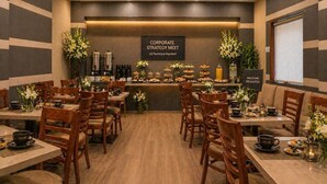 Sala de reuniões para estratégia corporativa, com mesas, cadeiras e espaço para buffet.