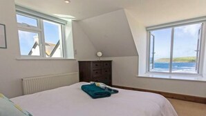 Quarto com cama, duas janelas, radiador e cómoda.