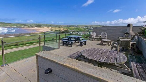 Um terraço com vista para a praia, mesas e cadeiras de piquenique.