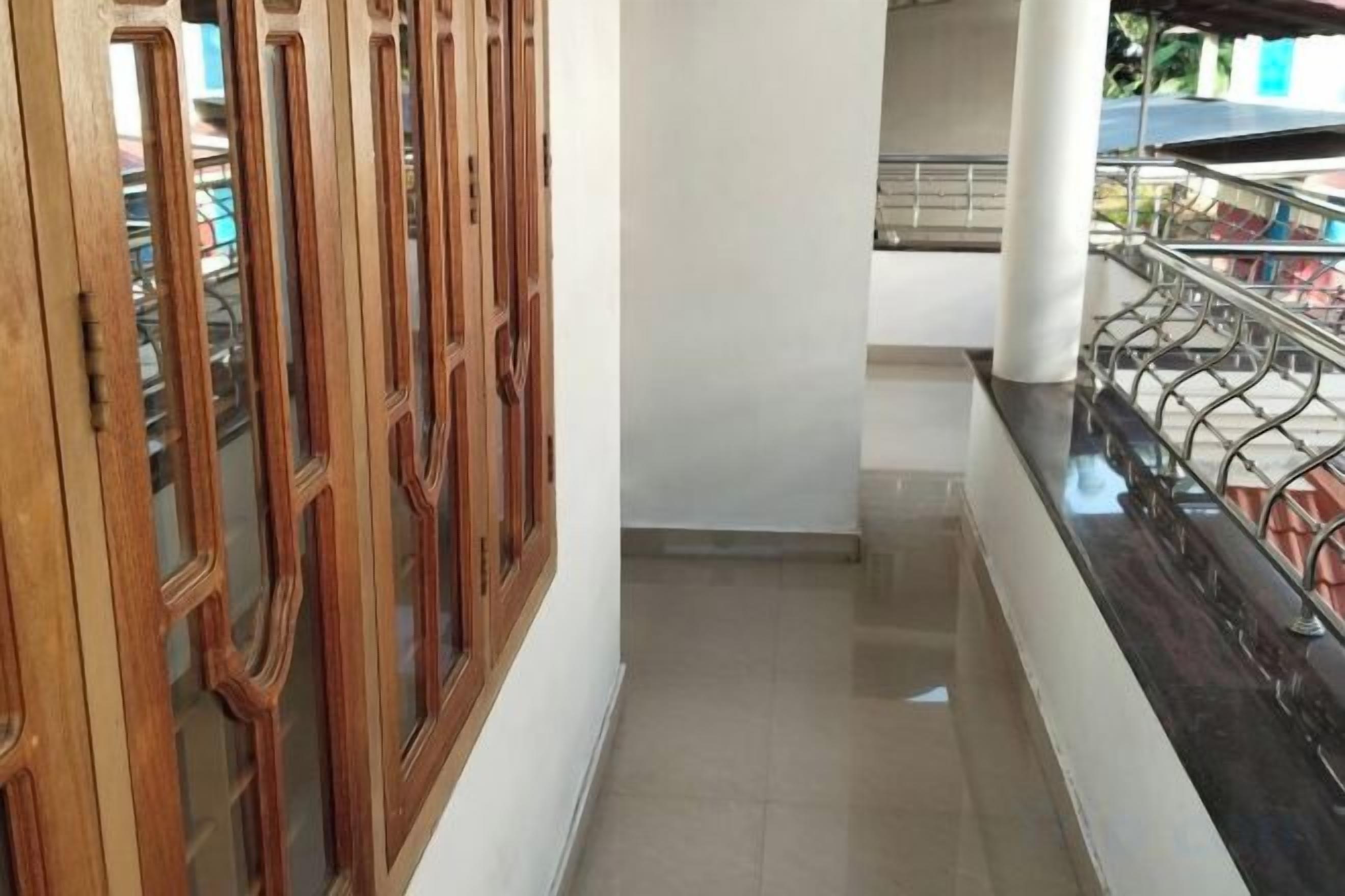 Corredor com porta de madeira e corrimão de metal à direita.