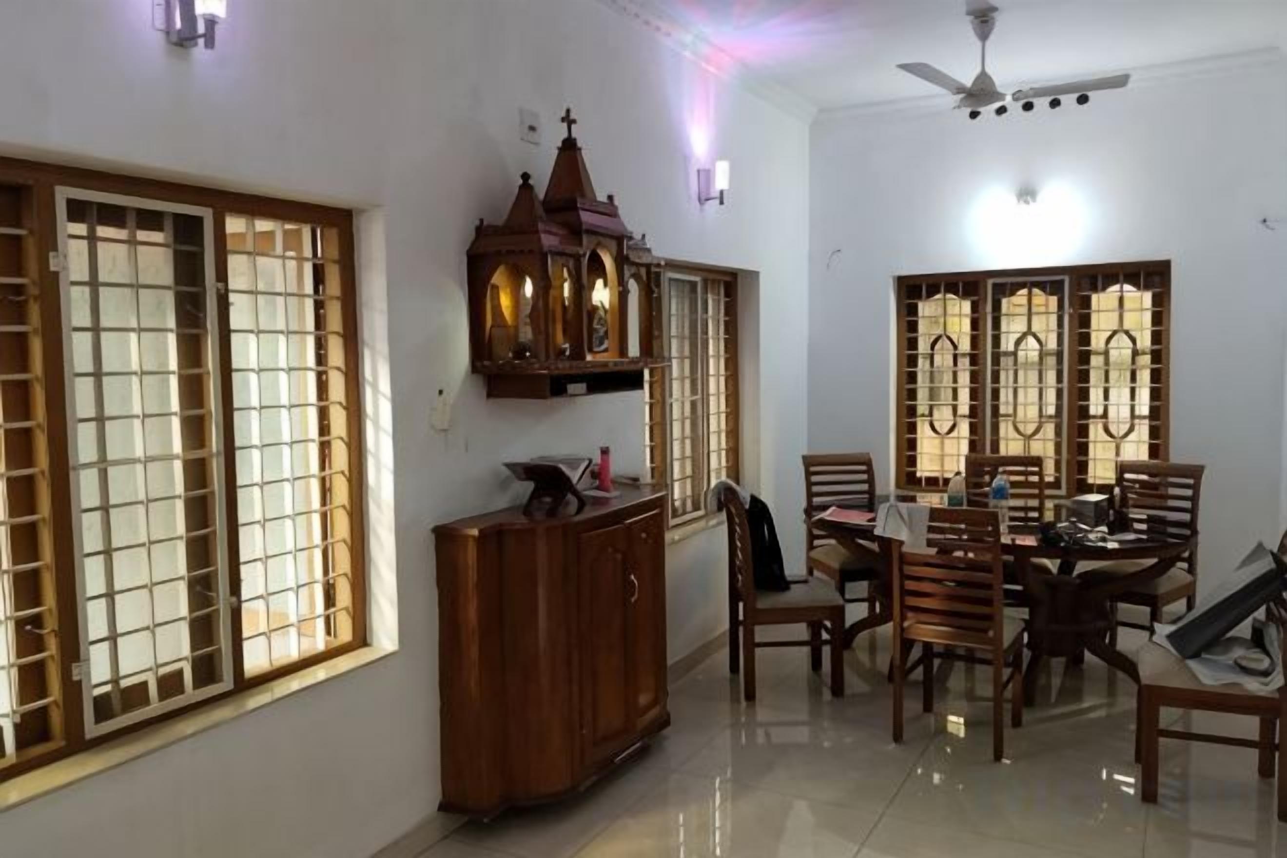 Uma área de refeições com mesa e cadeiras de madeira, um armário e um ventilador de teto.
