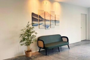 Uma área de recepção com um banco, uma planta em vaso e obras de arte nas paredes.