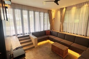 Uma sala de estar moderna com sofá em formato de L, uma mesa de centro e uma escada que leva a um andar superior.