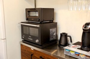 Cozinha equipada com micro-ondas, cafeteira e suporte para cápsulas de café.