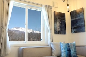 Quarto com uma janela grande, um sofá e duas pinturas abstratas na parede.