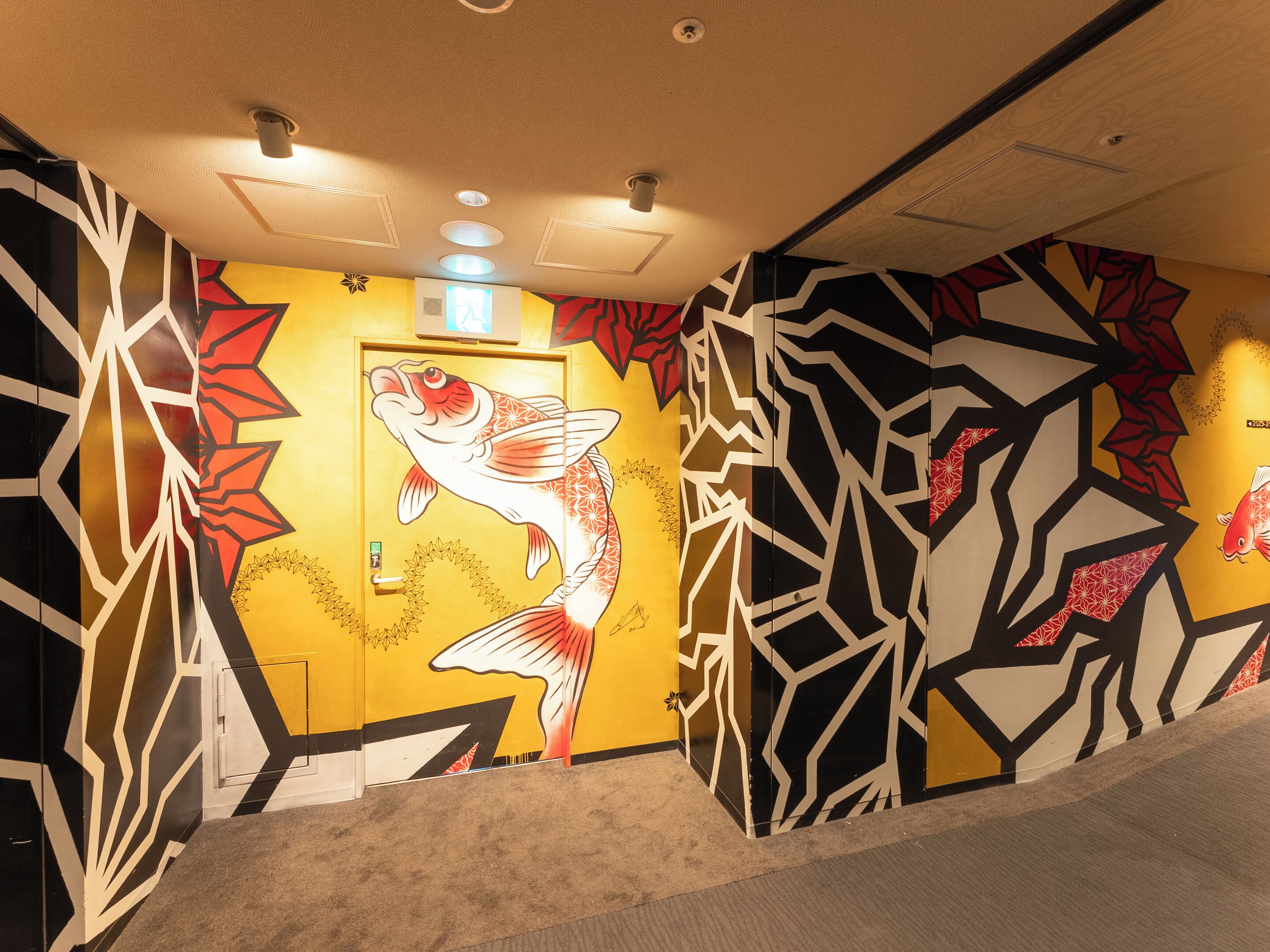 Corredor com um mural vibrante apresentando um peixe grande e padrões geométricos.