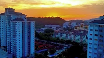 Um complexo de edifícios altos com vários andares, rodeado por outros edifícios e uma paisagem montanhosa ao fundo.