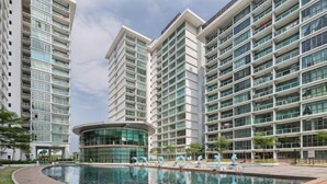 Um edifício residencial moderno com piscina, várias varandas e fachada de vidro curva.