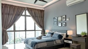 Quarto moderno com cama, mesas de cabeceira, escrivaninha e uma janela grande.