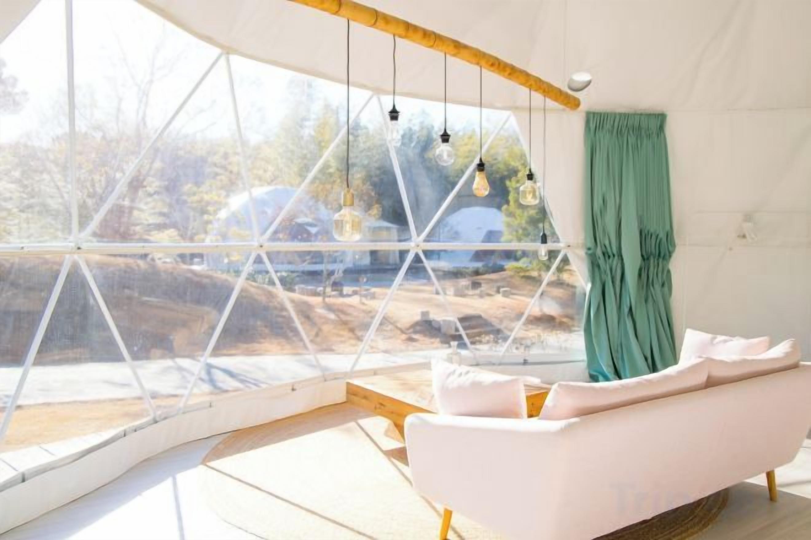 Um interior moderno com sofá branco, uma janela grande e luminárias pendentes.