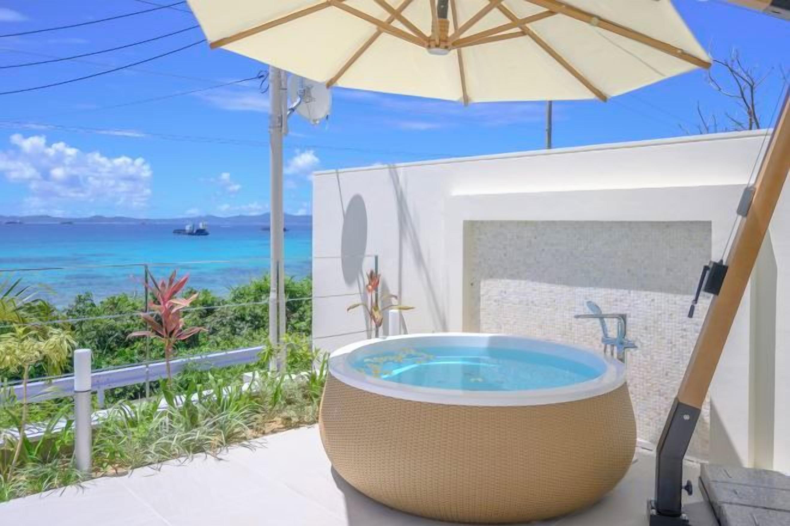 Ofurô com vista para o oceano, uma cadeira de praia e um guarda-sol.