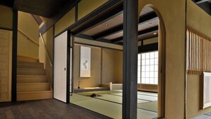 Um quarto tradicional com esteiras de tatame, uma porta deslizante, uma escada de madeira e vista pela janela.