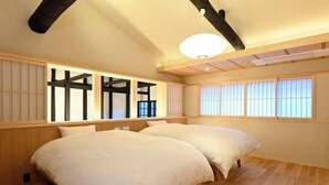Um quarto tradicional japonês com piso de tatame, teto baixo com vigas aparentes e portas corrediças shoji.