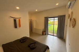 Quarto com cama, guarda-roupa, um banco e vista para o exterior.