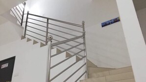 Uma escadaria com corrimão de metal, degraus bege e uma porta com a placa 'No Entry'.