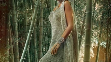 Uma pessoa com vestido estampado em meio a um bosque de bambu.