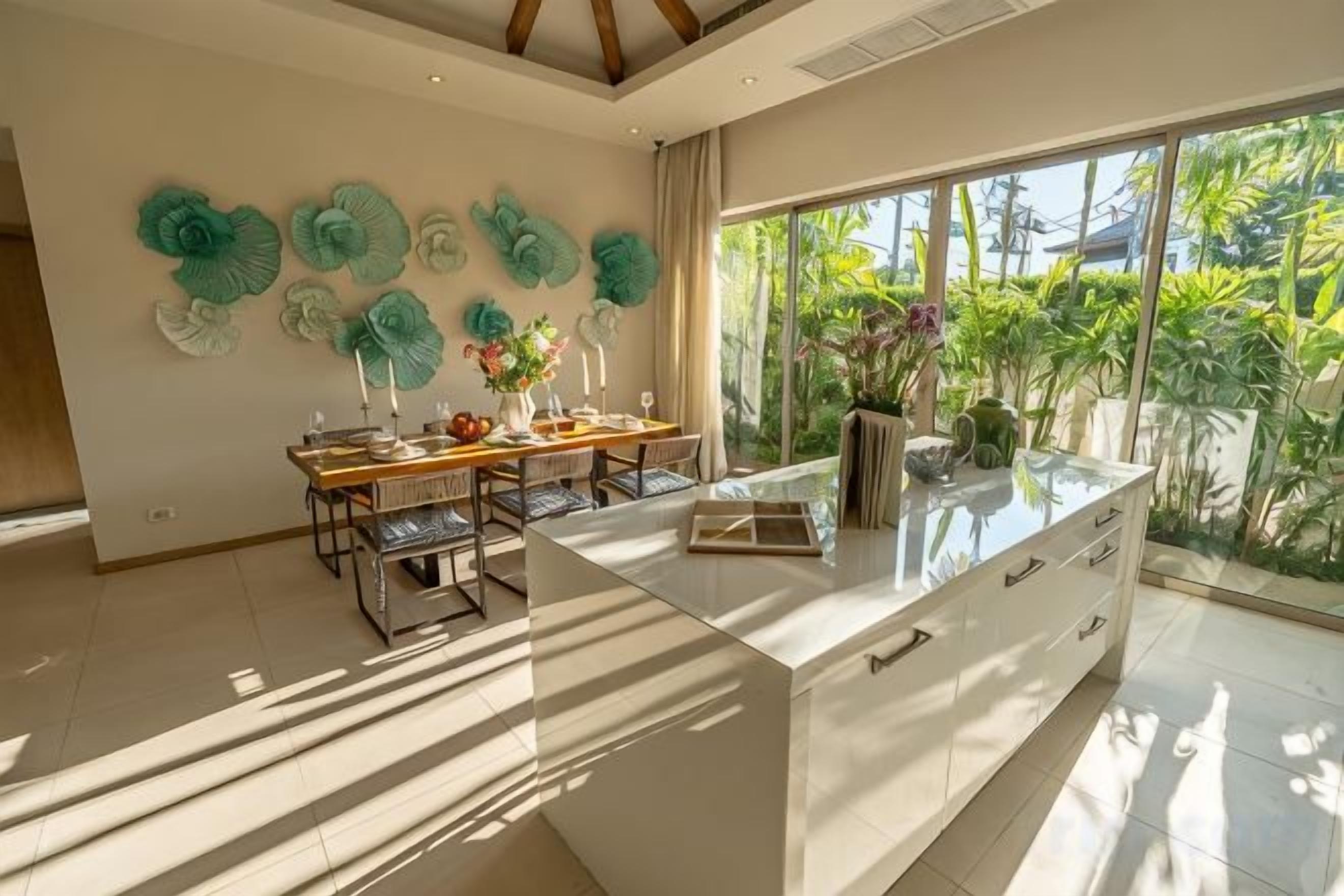 Cozinha moderna com uma ilha grande, área de jantar com mesa e cadeiras, e vista para o verde lá fora.