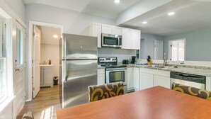 Uma cozinha moderna com eletrodomésticos de aço inoxidável, armários brancos e uma mesa de jantar de madeira.