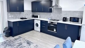 Uma cozinha moderna com armários escuros, máquina de lavar, micro-ondas e fogão.