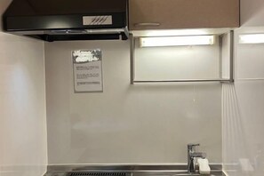 Casa de banho com lavatório de aço inoxidável, espelho e dispensador de toalhas.
