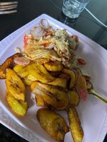 Um prato com platanos fritos, ovos mexidos e cebola fatiada.