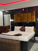 Quarto de hotel moderno com uma cama grande, cabeceira com design acolchoado e espelho com moldura de mármore.