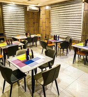 Um restaurante com várias mesas e cadeiras, aparelhos de ar condicionado e piso de azulejos.