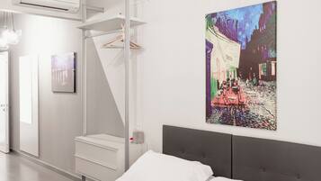 Quarto de hotel moderno com cama, guarda-roupa, cadeira suspensa e um quadro de uma cena urbana.