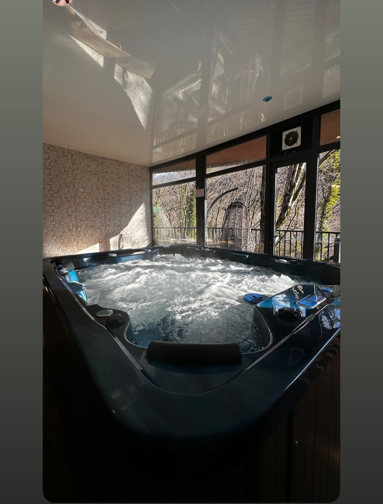 Banheira de hidromassagem com vista para árvores através de grandes janelas.