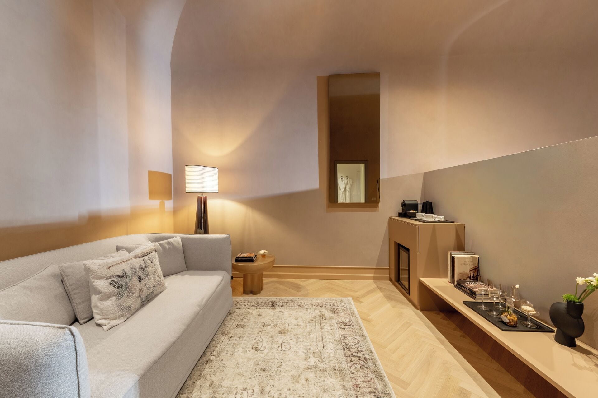 Uma sala de estar moderna com um sofá, uma mesa de centro, um abajur e uma mesinha lateral.