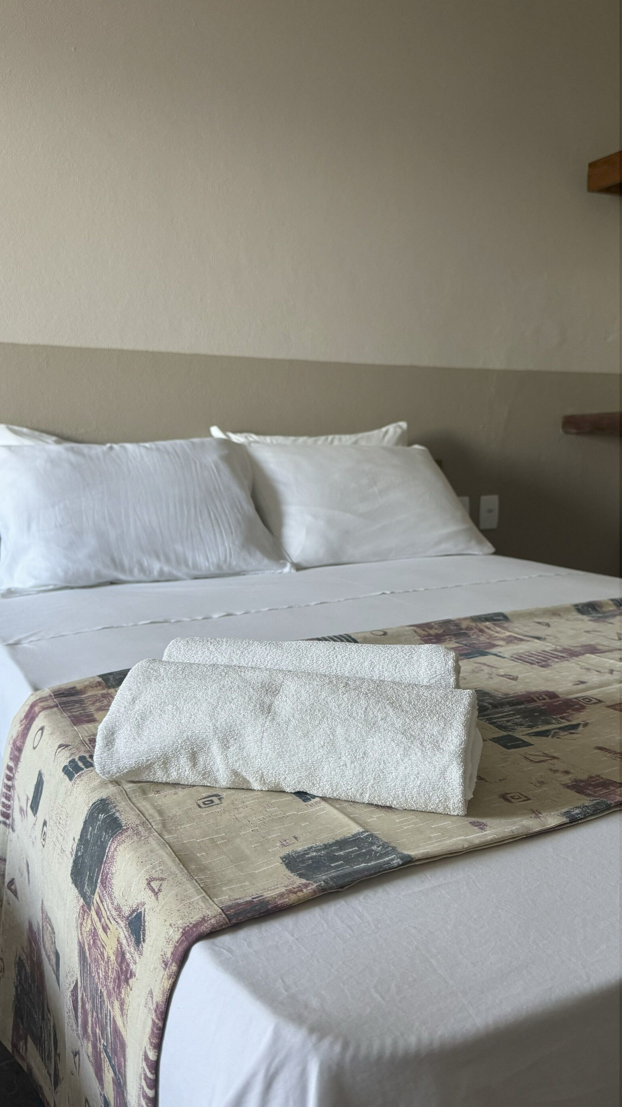 Cama bem arrumada com roupa de cama branca e manta decorativa.