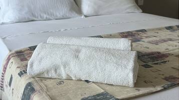 Cama bem arrumada com roupa de cama branca e manta decorativa.