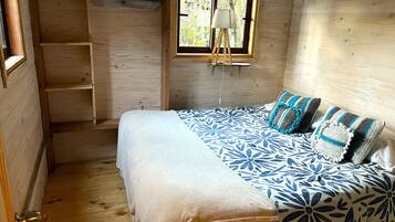 Quarto de madeira com uma cama, uma janela e uma porta.