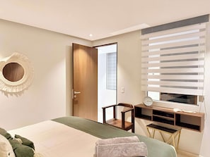 Um quarto com uma cama, uma escrivaninha, uma cadeira, um relógio na parede e uma janela com persianas.