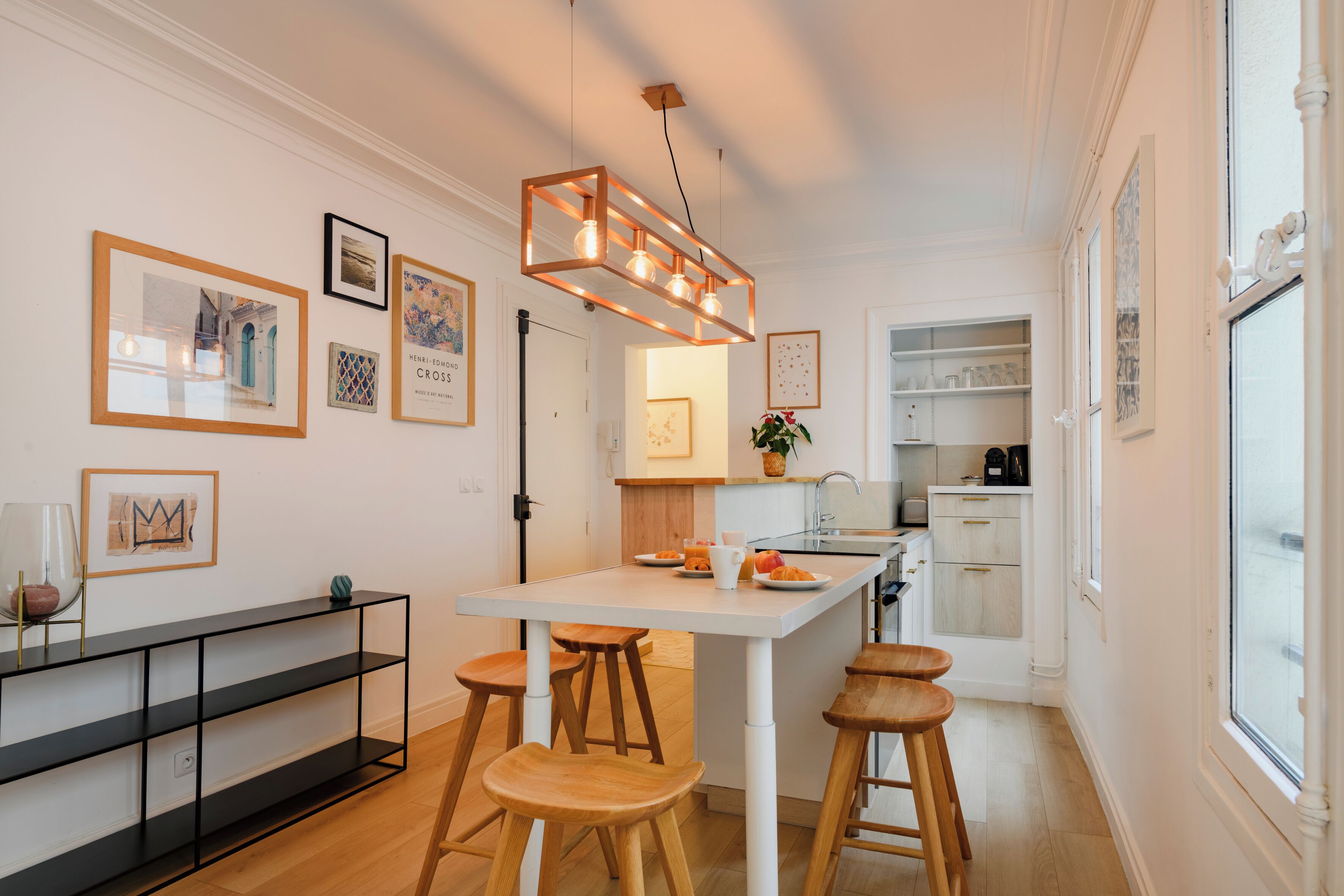 Uma cozinha moderna com ilha central, banquetas de bar e luminária pendente.