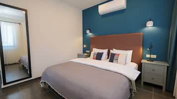 Quarto com cama, mesas de cabeceira, espelho e aparelho de ar condicionado.