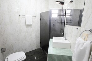 Uma casa de banho com sanita, cabine de duche, lavatório e espelho.
