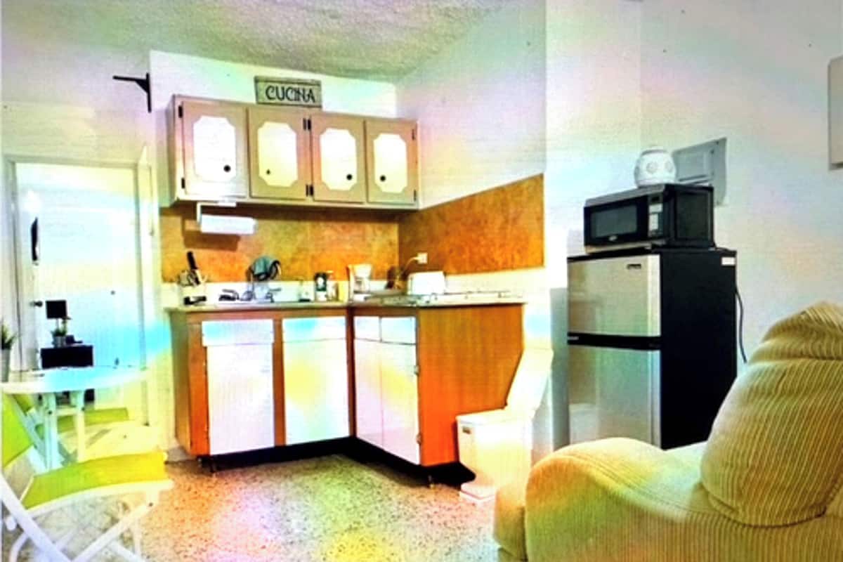 Uma cozinha compacta com uma ilha central, micro-ondas e geladeira.