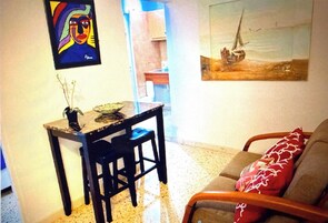 Uma sala de jantar com mesa e cadeiras, um quadro na parede e vista para o exterior.