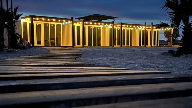 Um edifício moderno com várias portas iluminadas e uma área externa coberta decorada com luzes de cordão.