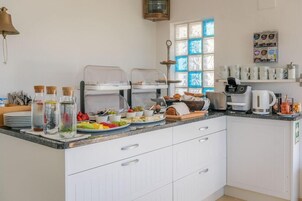 Cozinha moderna com balcão de café da manhã, diversos alimentos e um espaço para café.