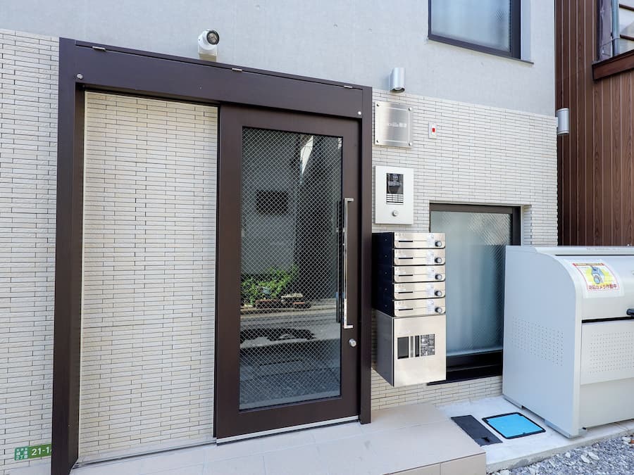 Um edifício moderno com porta de metal, câmera de segurança e máquina de vendas.