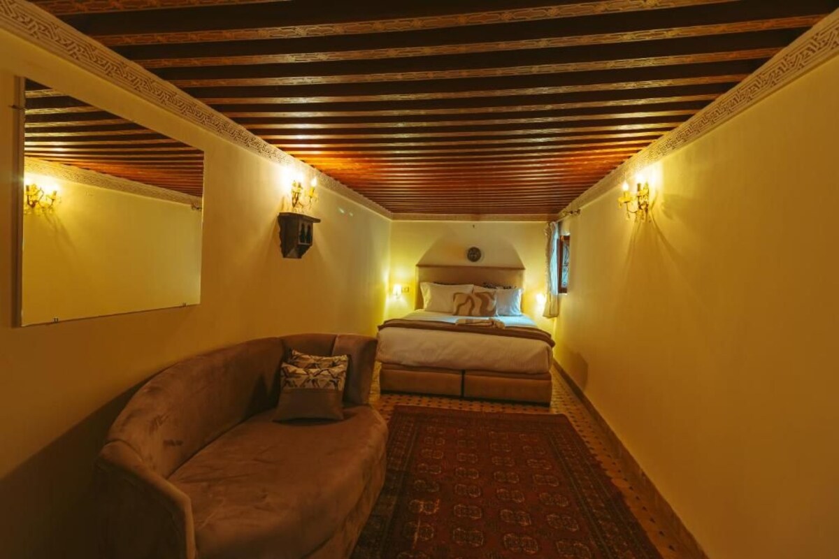 Um quarto aconchegante com uma cama, um sofá e um tapete estampado.