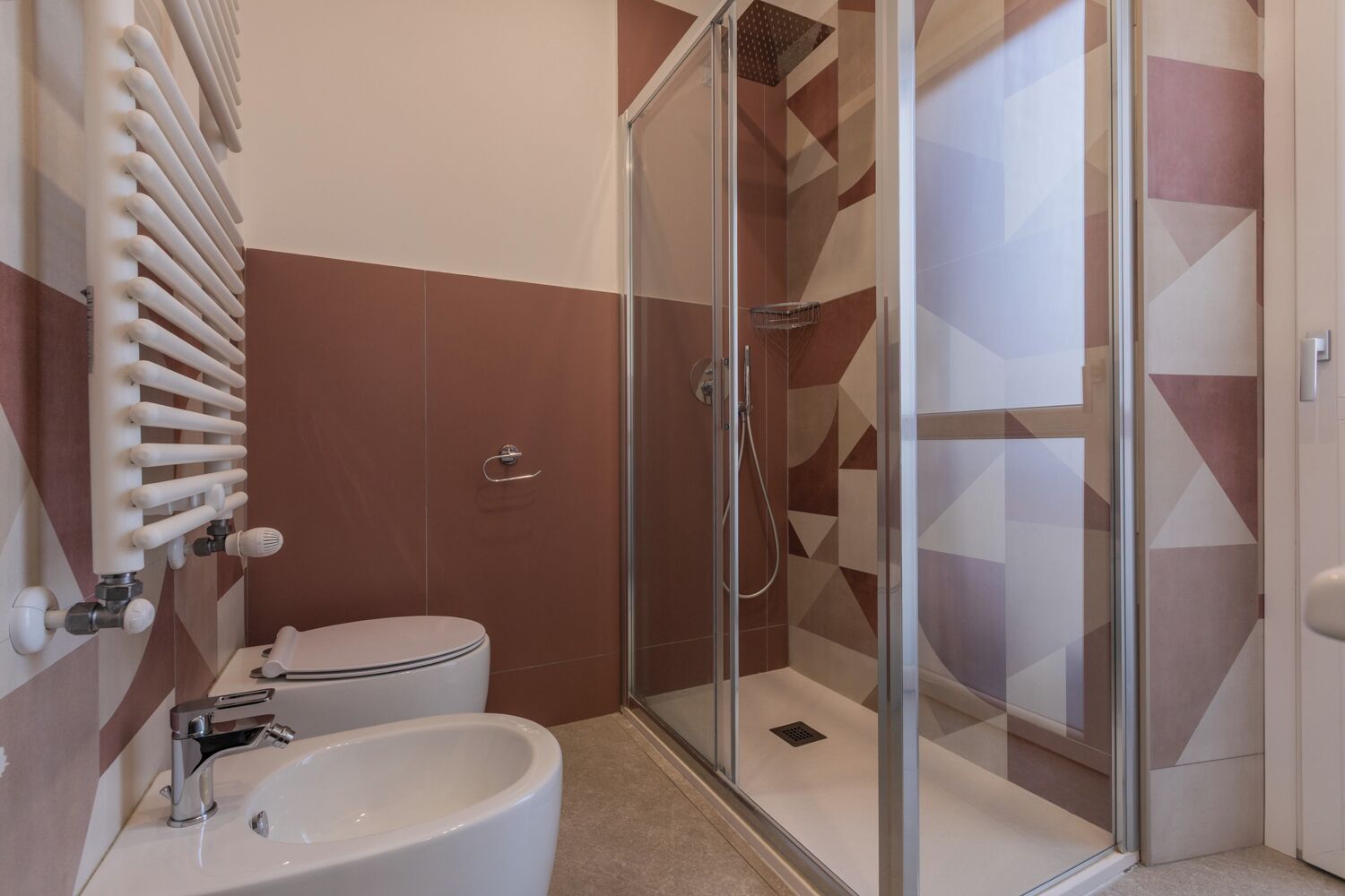 Uma casa de banho moderna com cabine de duche em vidro, sanita e lavatório.