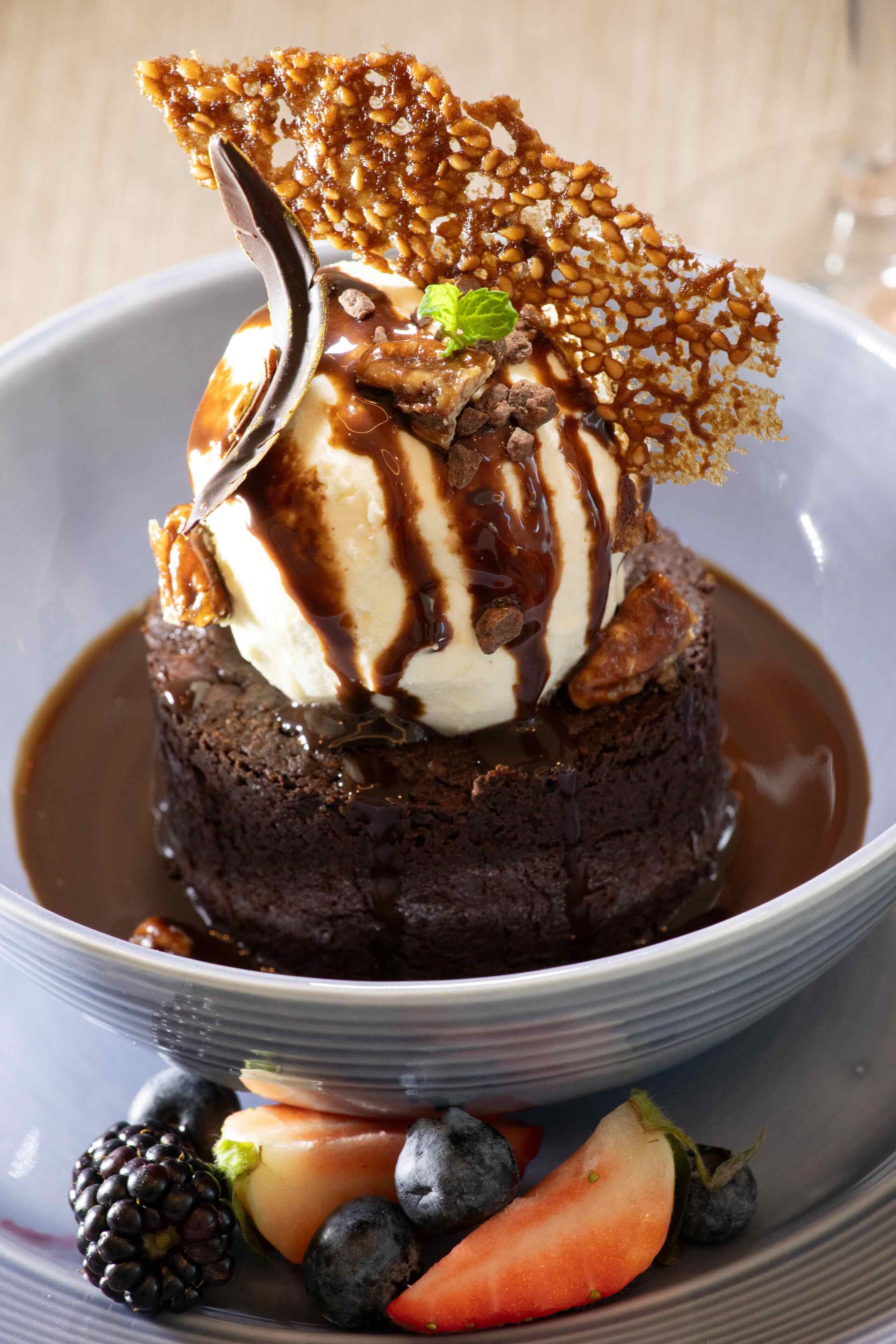 Sobremesa com bolo de chocolate, gelado e molho de caramelo.