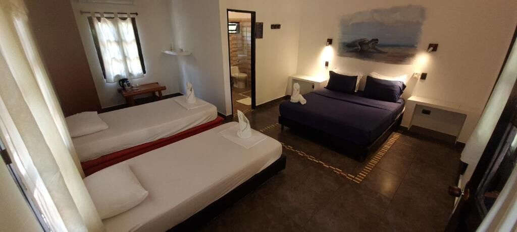 Quarto de hotel com duas camas de solteiro, uma cama grande, um quadro na parede e vista do quarto.